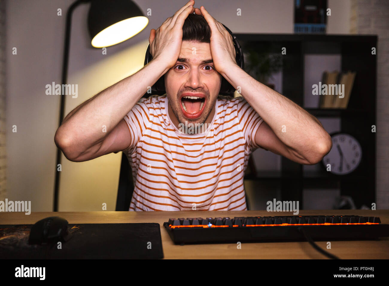 Portrait of stressed gamer guy grabbing head while playing video games ...