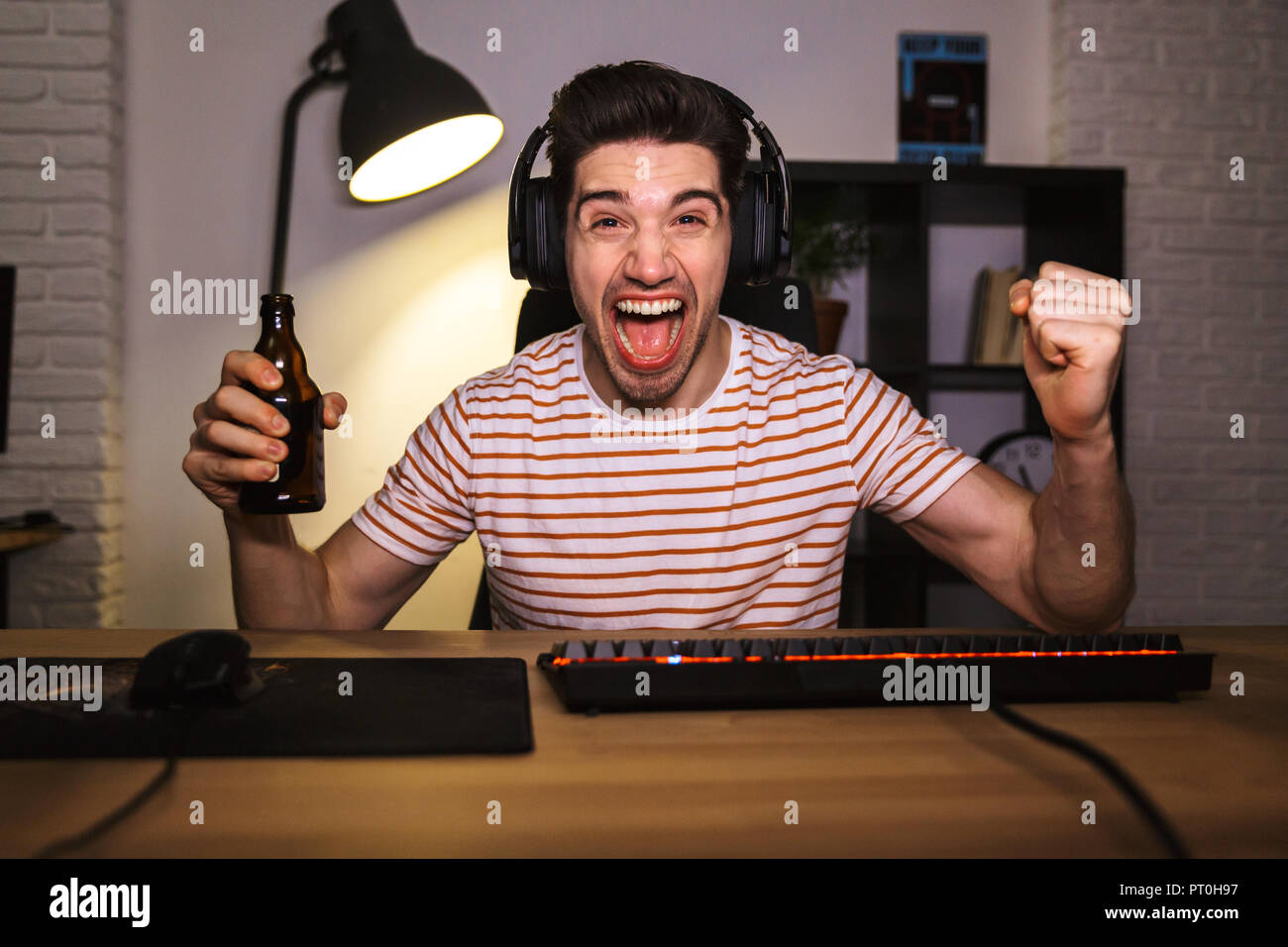Image of european guy 20s wearing headphones drinking beer while ...