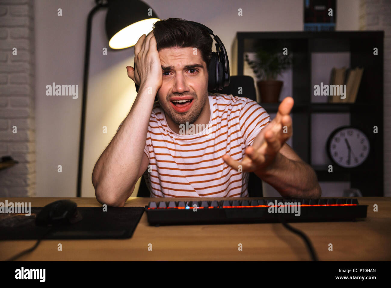 Confused gamer playing video games on computer while sitting by the ...