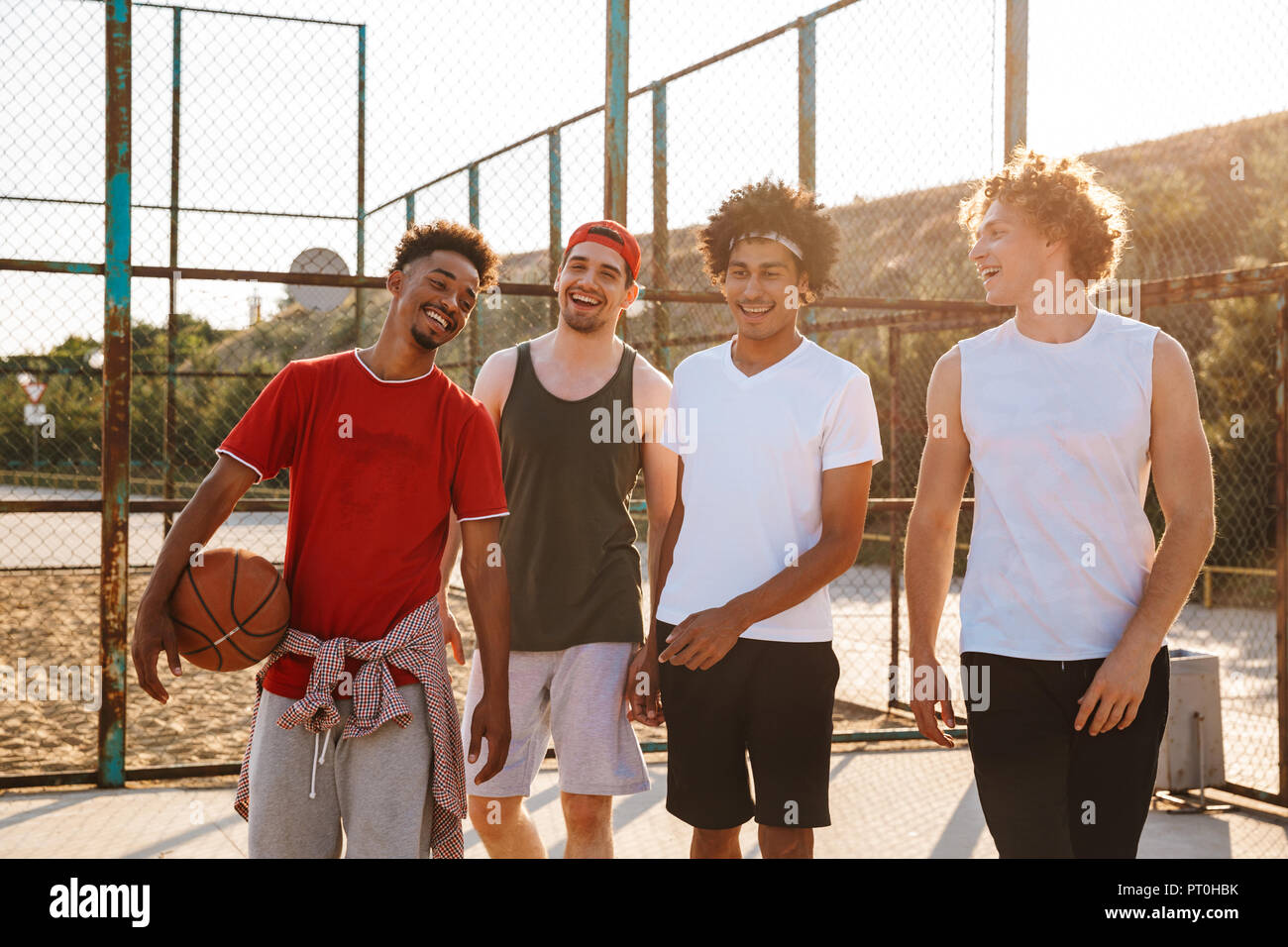 Portrait of young sporty men playing basketball at the playground ...