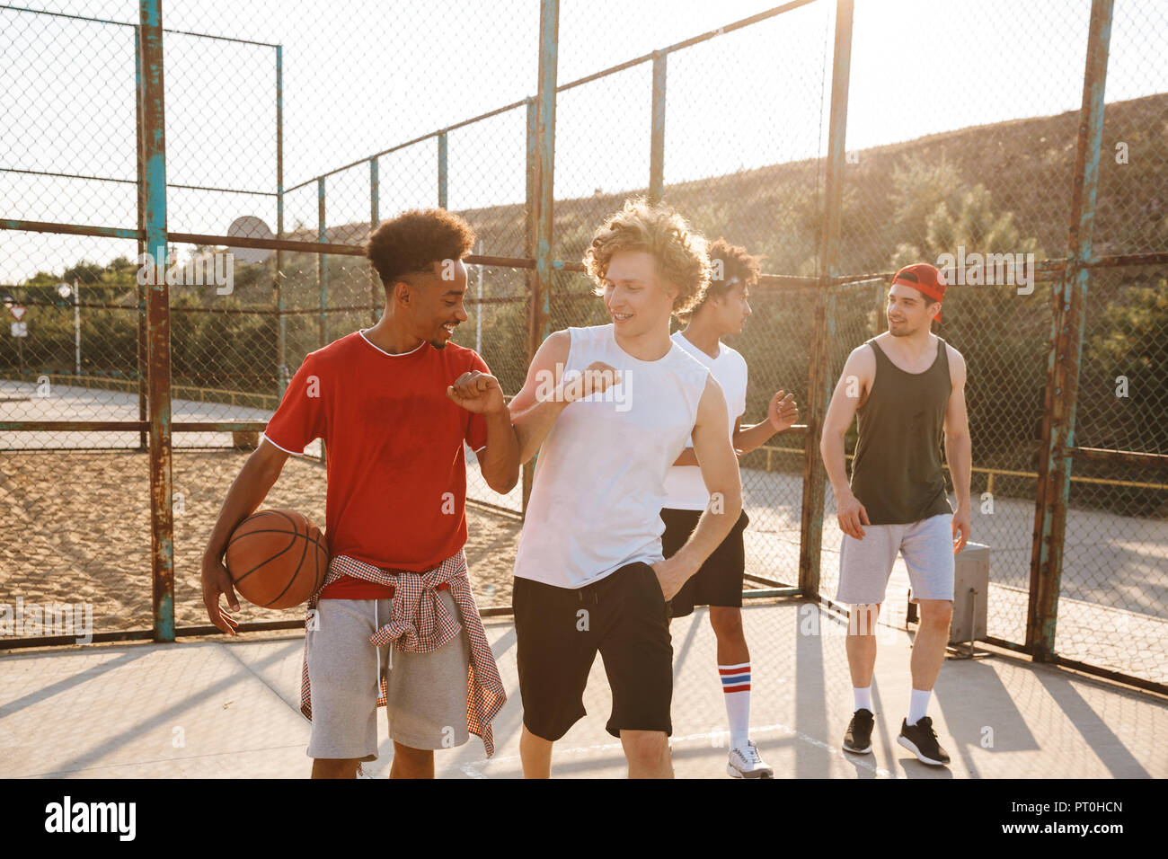 Portrait of joyful young guys basketball players walking along ...