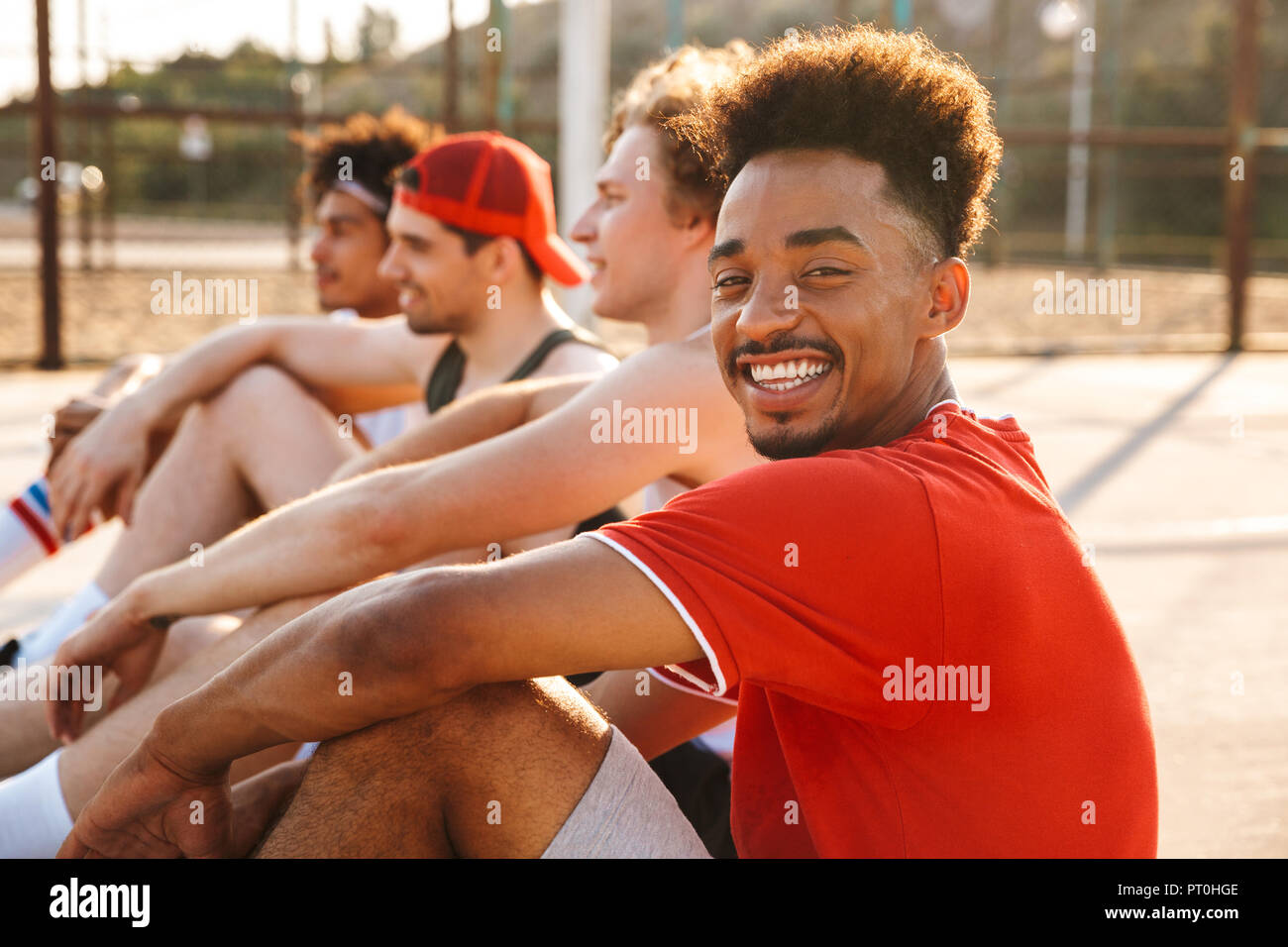 Group of young joyful multiethnic men basketball players resting at the ...
