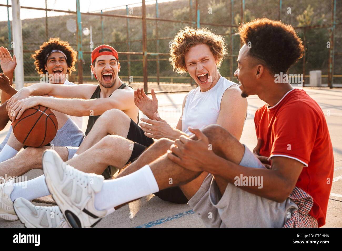 Group of young cheerful multiethnic men basketball players resting at ...