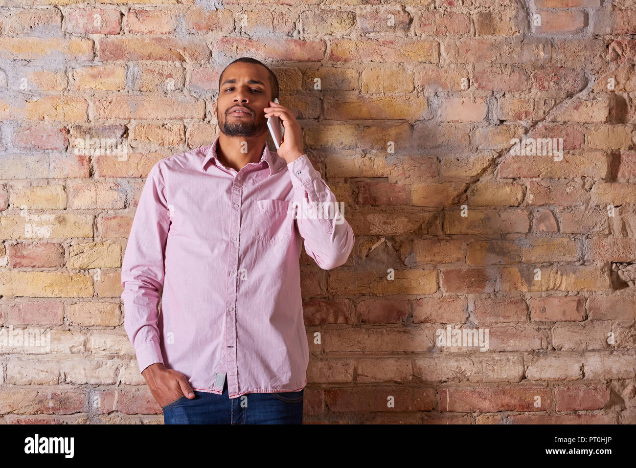 A serious handsome young man talking on his phone in a pink shirt Stock ...