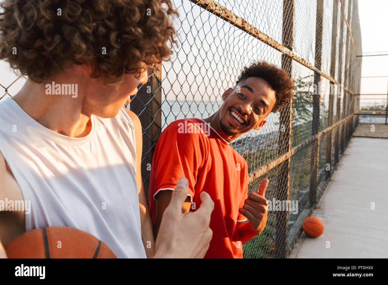 Two young smiling multiethnic men basketball players standing at the ...