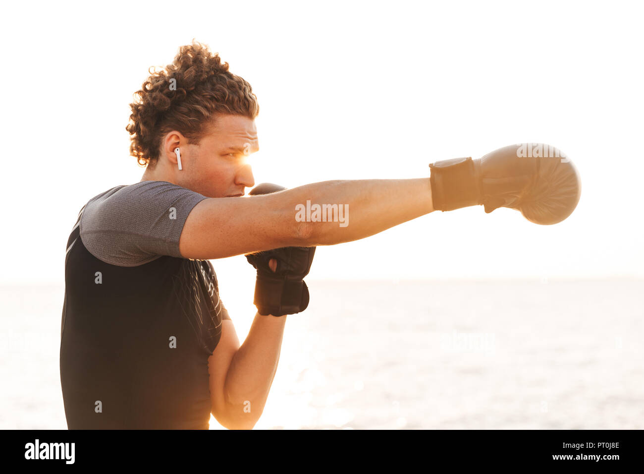 Photo of young handsome sports man boxer outdoors on the beach boxing ...