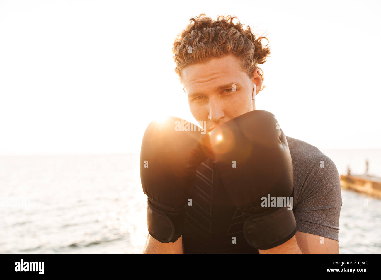 Photo of young handsome sports man boxer outdoors on the beach boxing ...