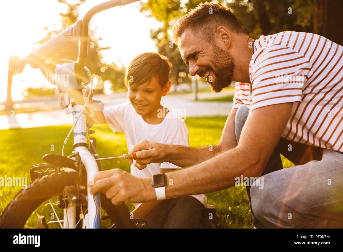 Happy father and his son having fun together at the green park, fixing ...