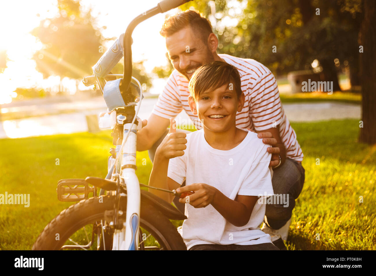 Laughing father and his son having fun together at the green park ...