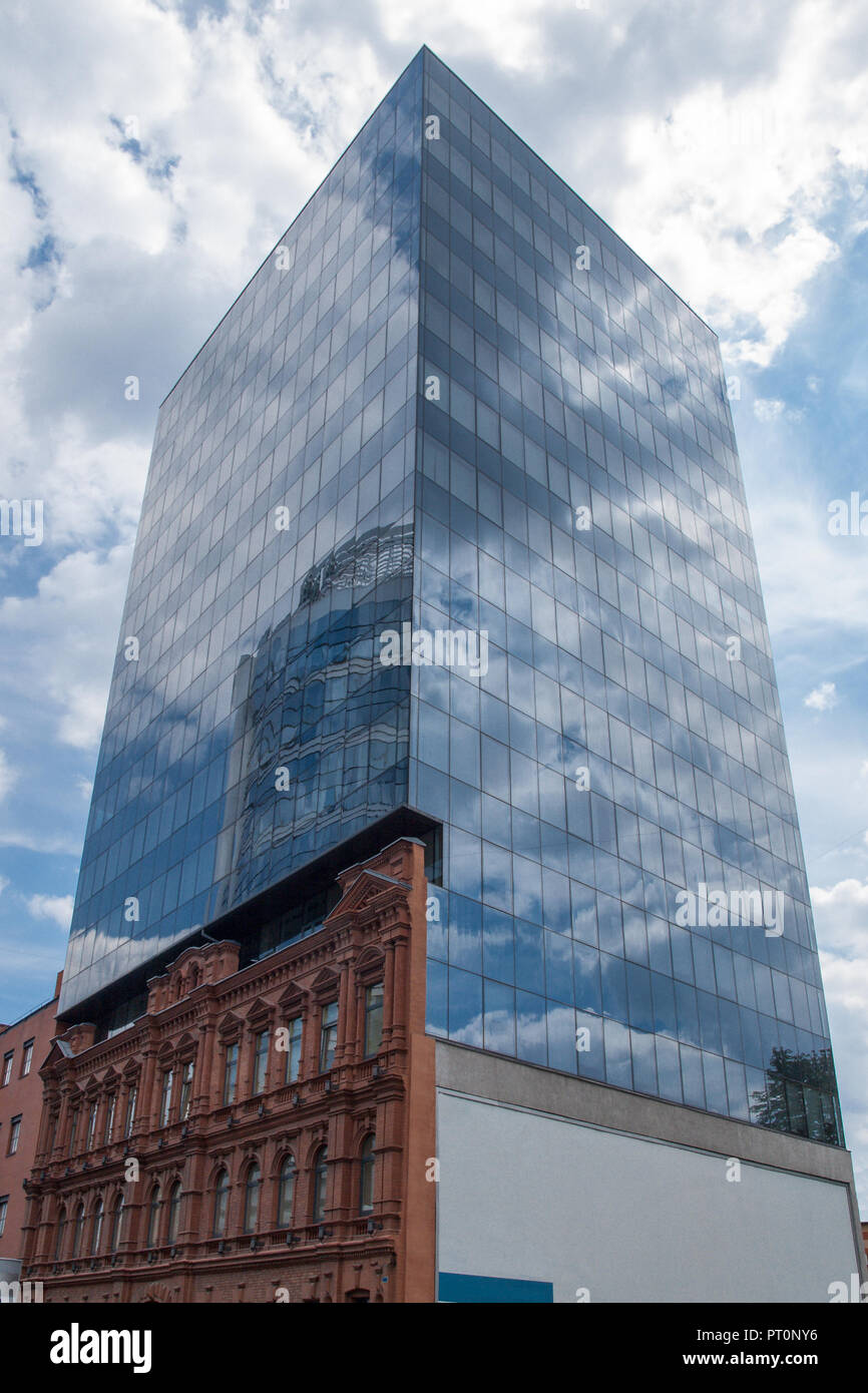 Modern high-rise building with walls reflecting bright blue sky and ...