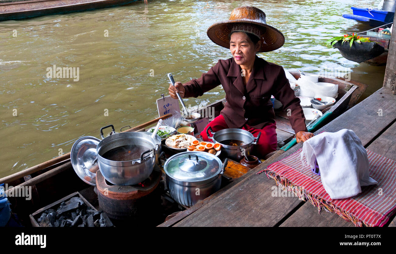 Female food vendor wearing traditional large straw hat at the Damnoen ...