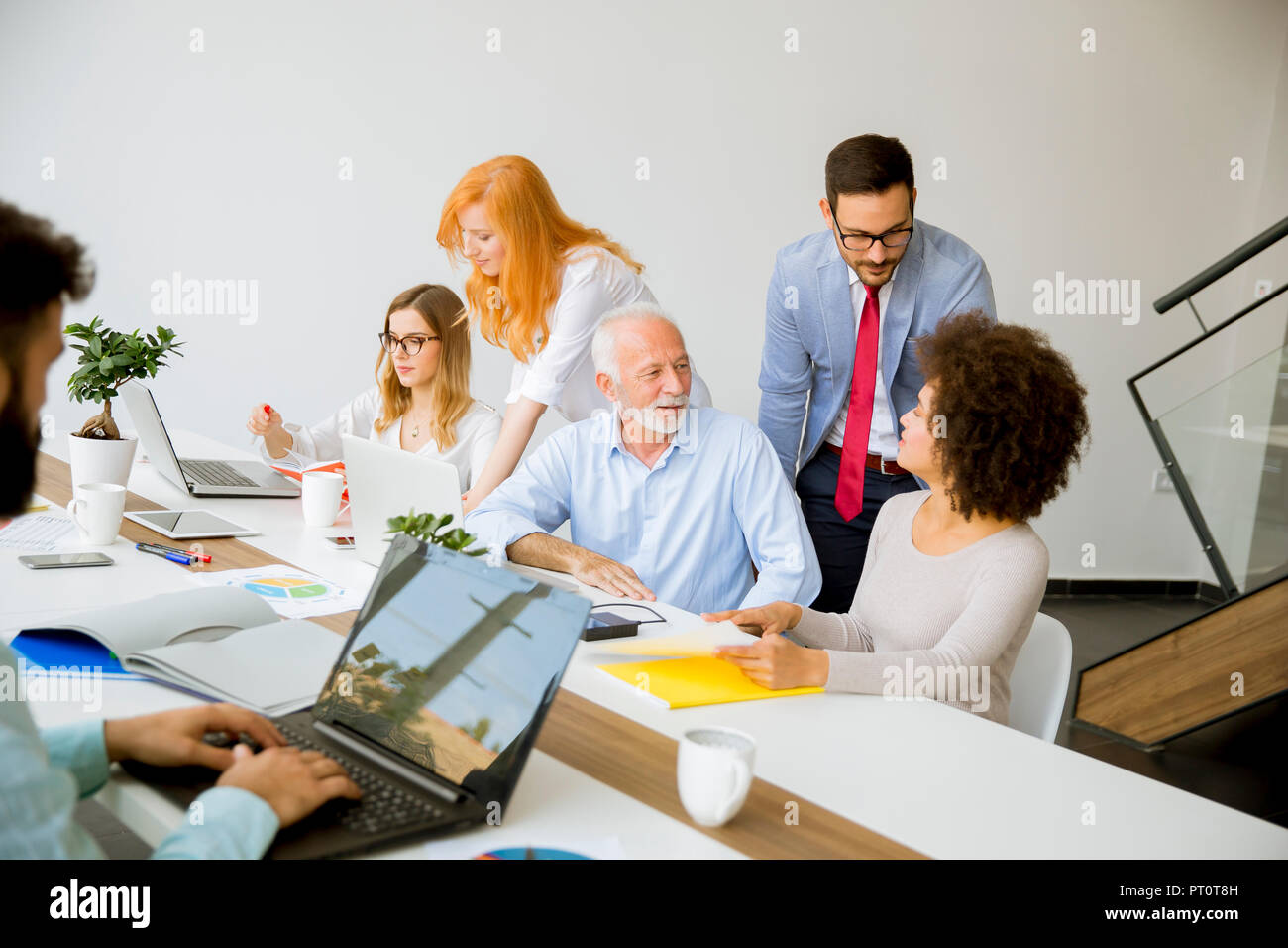 View at group of young multiracial business people around table during ...