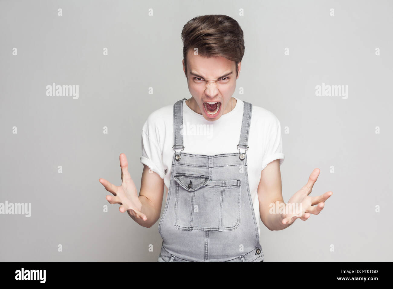 Portrait of angry young brunette man in casual style with t-shirt and ...