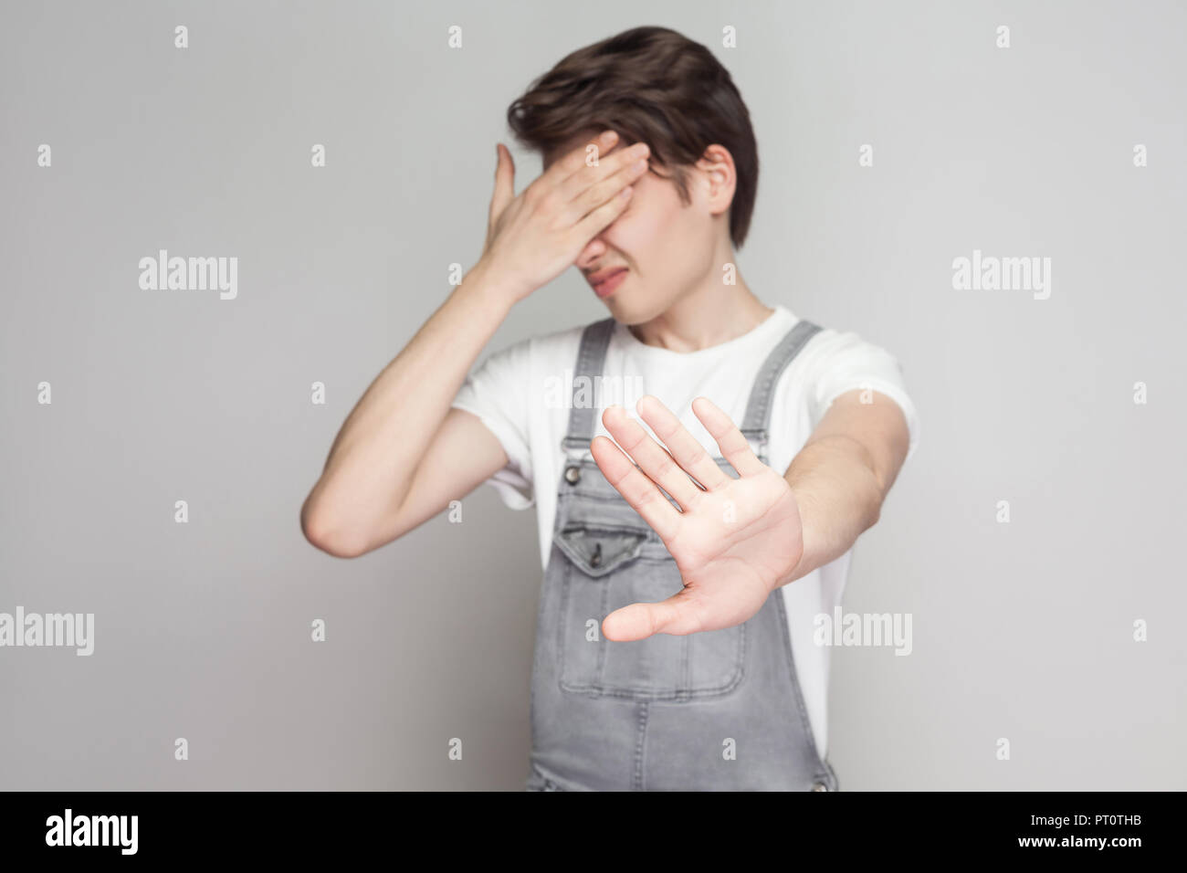 Portrait of scared or shy young brunette man in casual style with denim ...