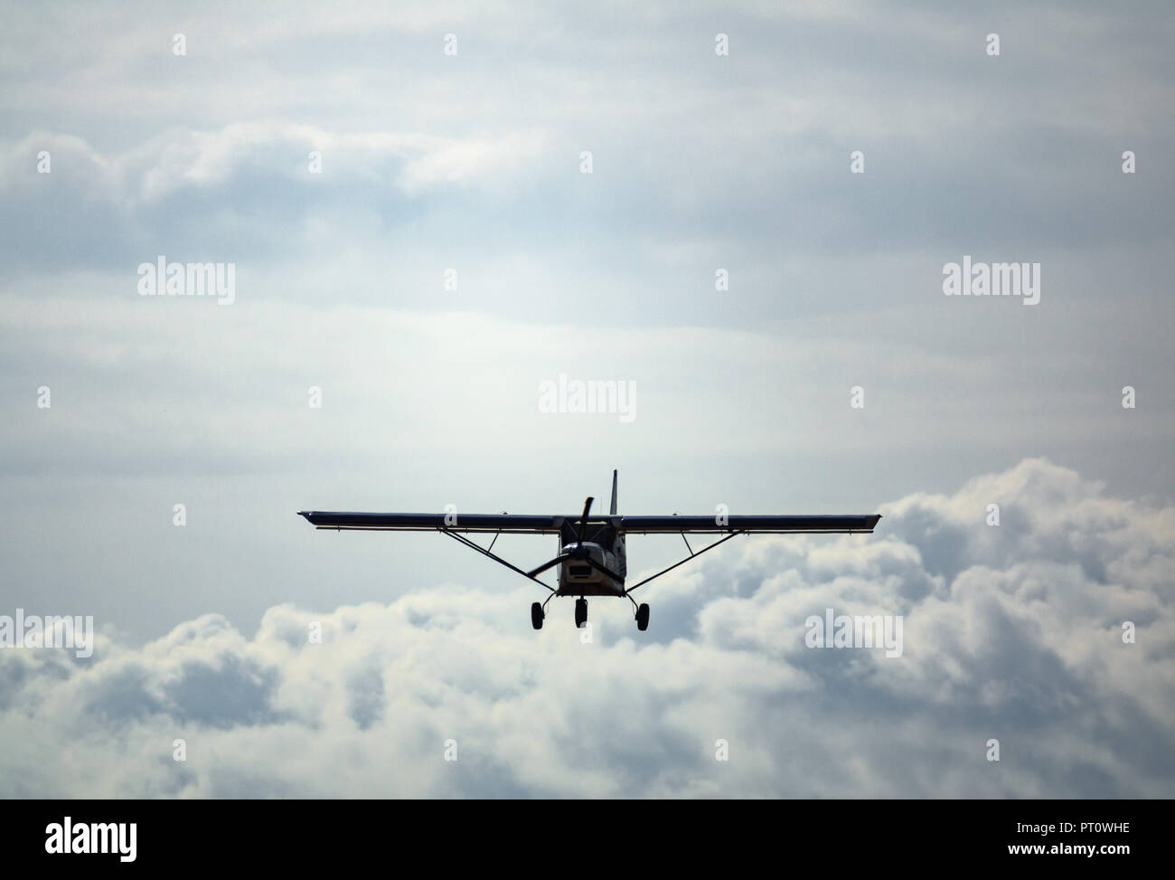 Light aircraft flying over cloudy sky, front view Stock Photo - Alamy