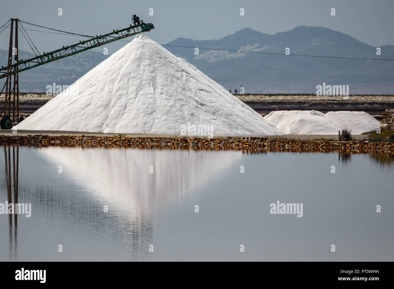 Saltmine pile with machines and water reflection Stock Photo - Alamy