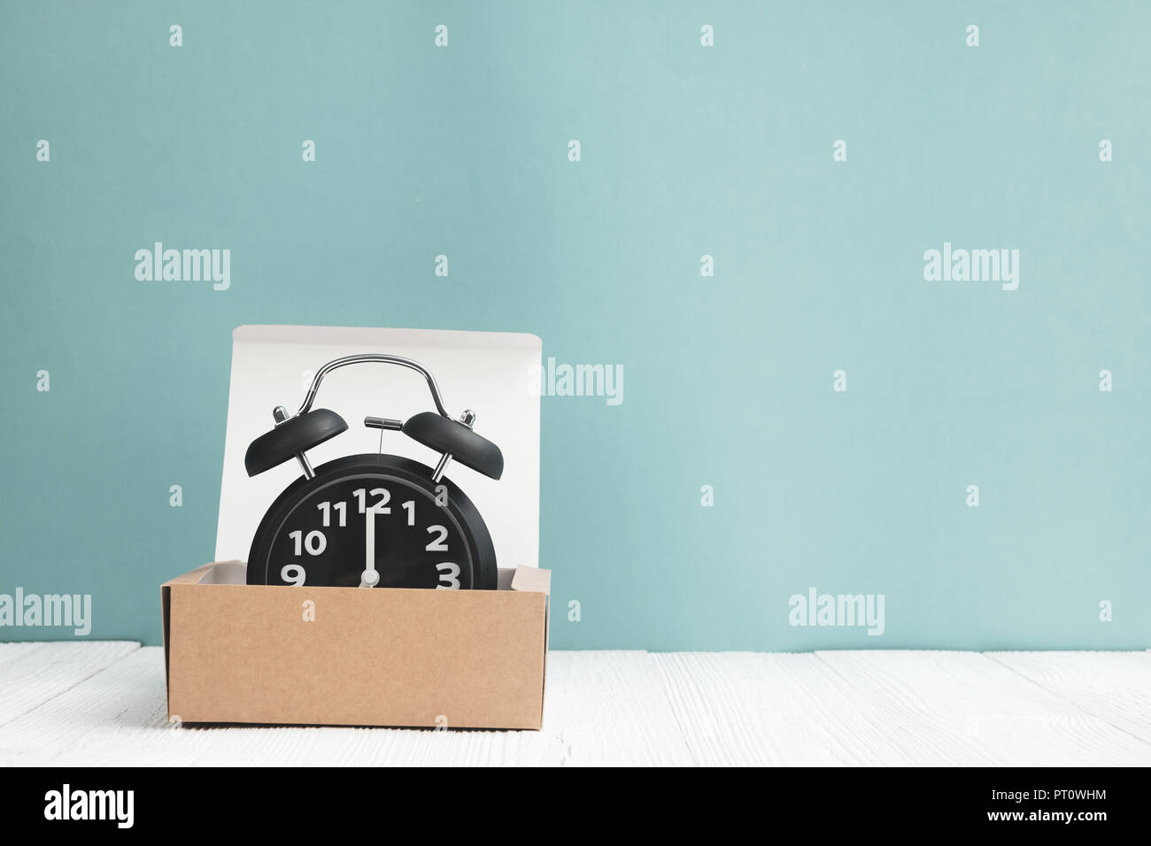 Retro alarm clock in brown delivery cardboard box or tray on white wood ...