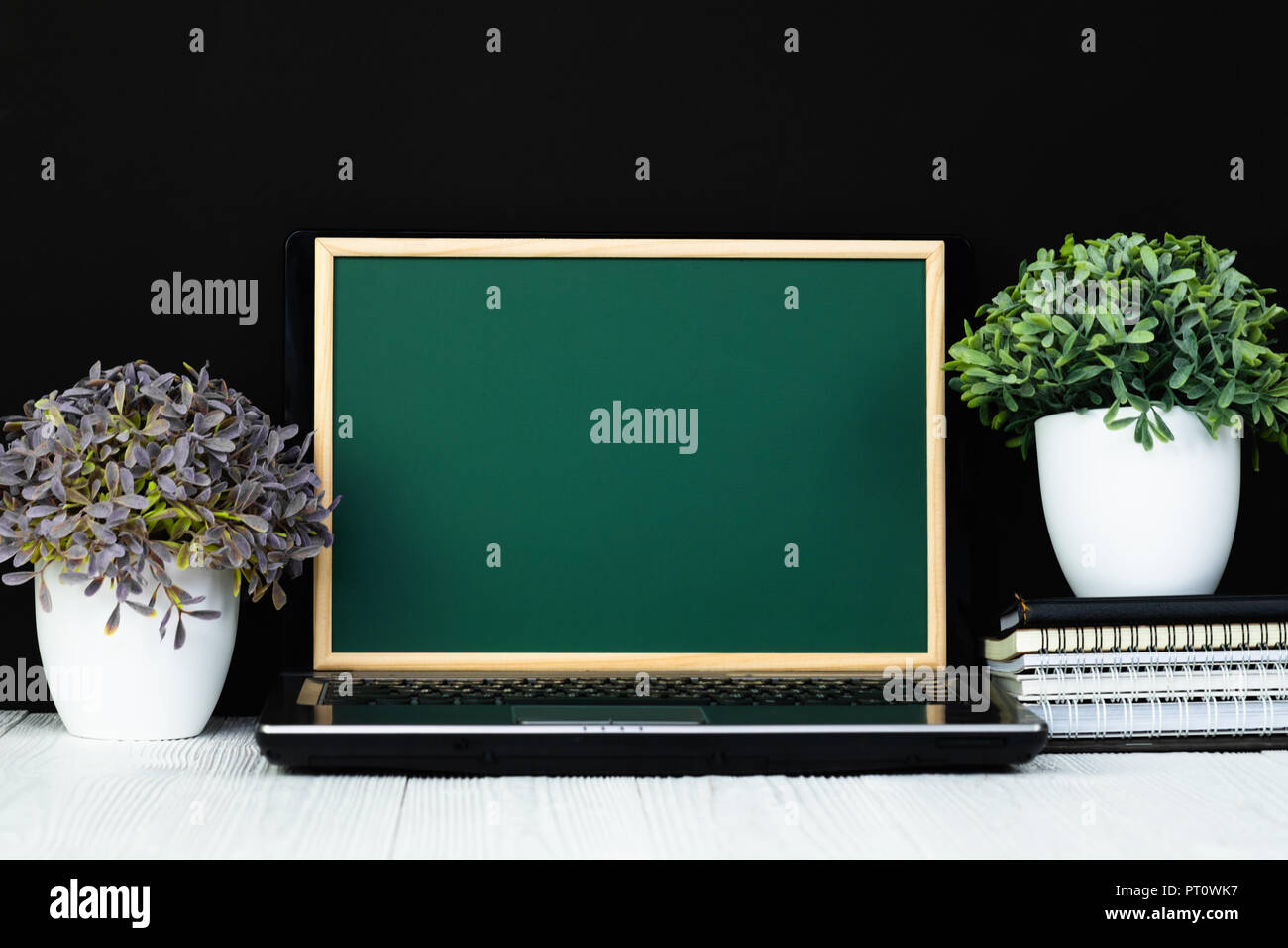 Notebook laptop computer with green chalkboard screen and pile of ...