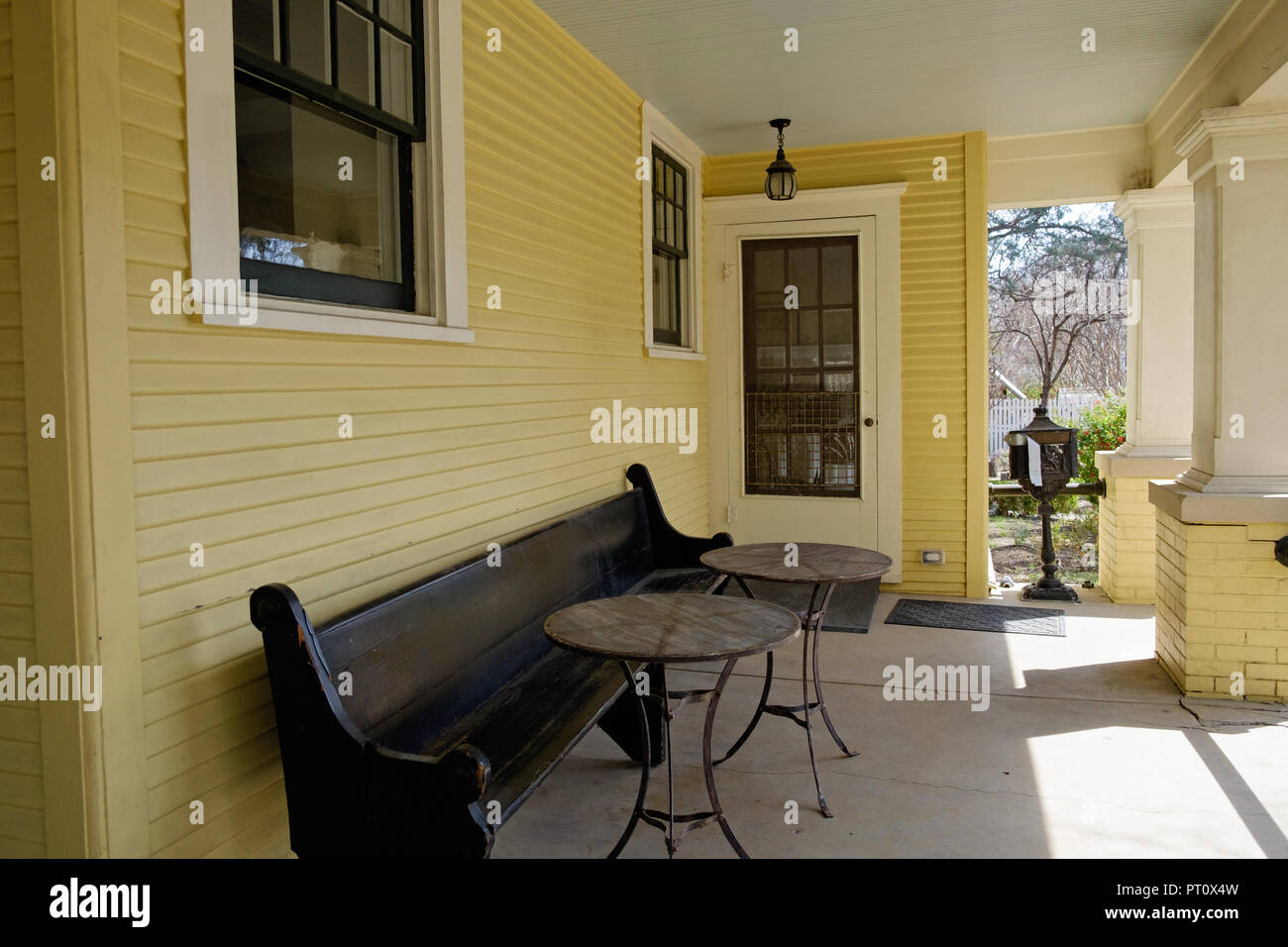 Historic house veransa, long wooden bench & 2 round tables. Yellow ...