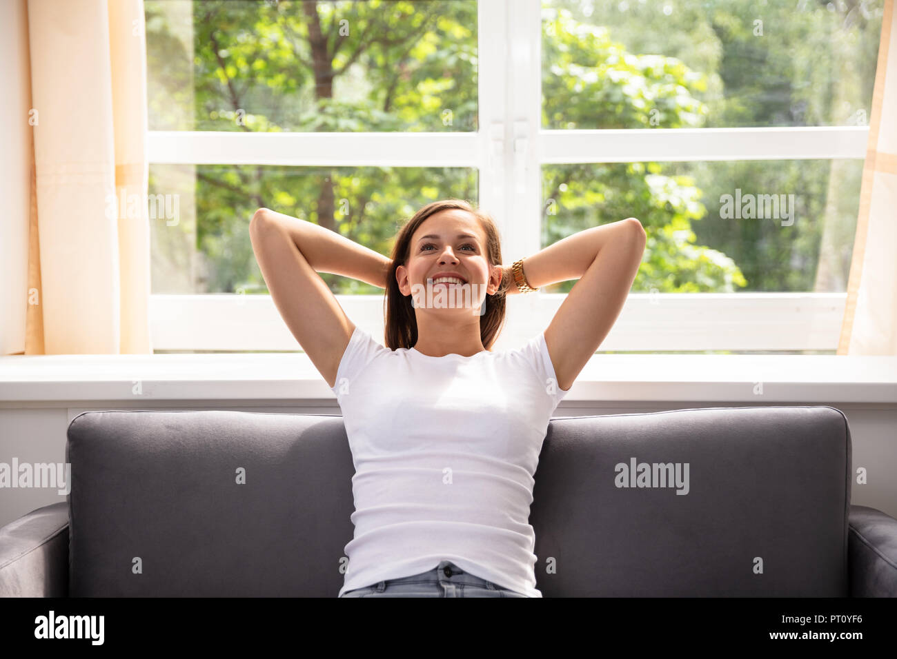 Portrait Of A Relaxed Woman Sitting On Sofa Stock Photo - Alamy