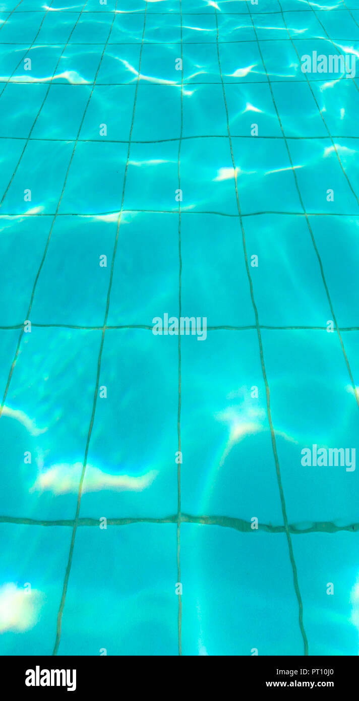Sun reflection on the clear water ripples of swimming pool with tiles ...