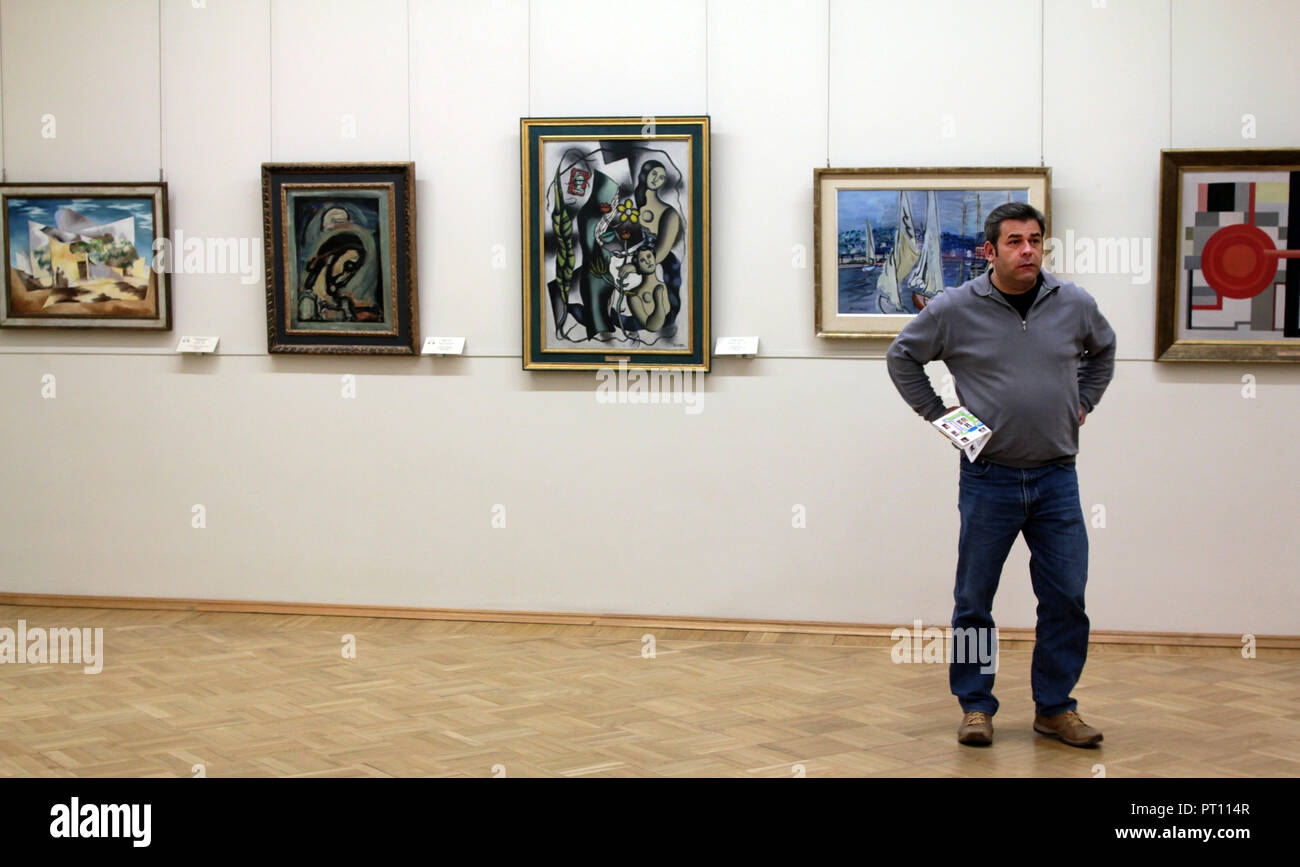 A member of the public wandering around a gallery of paintings in an ...