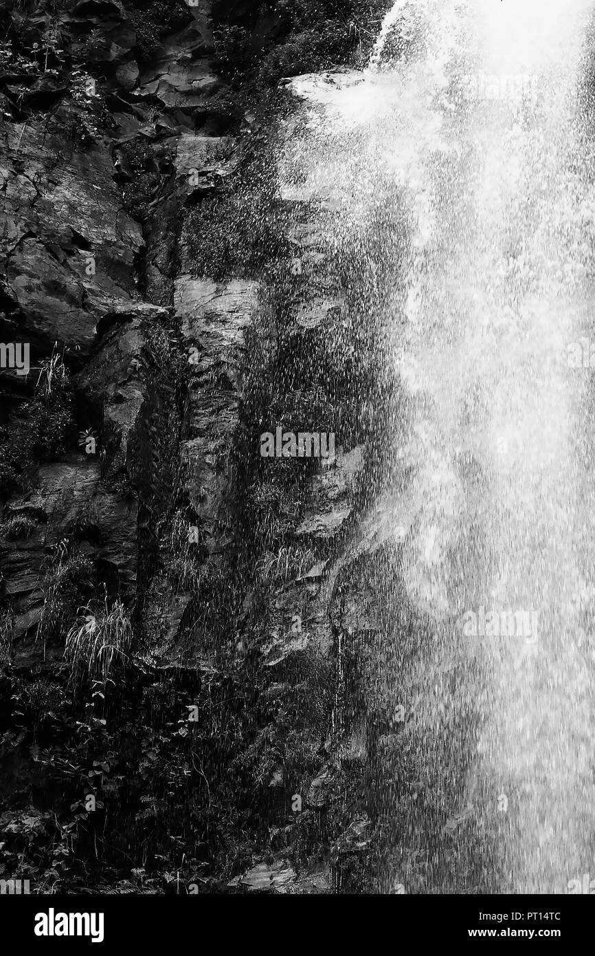 Black and white image half waterfall and half wet cliffside close up ...