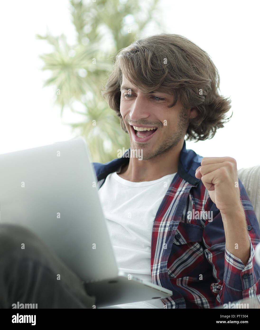 very happy guy with a laptop sitting near a coffee table. photo with ...