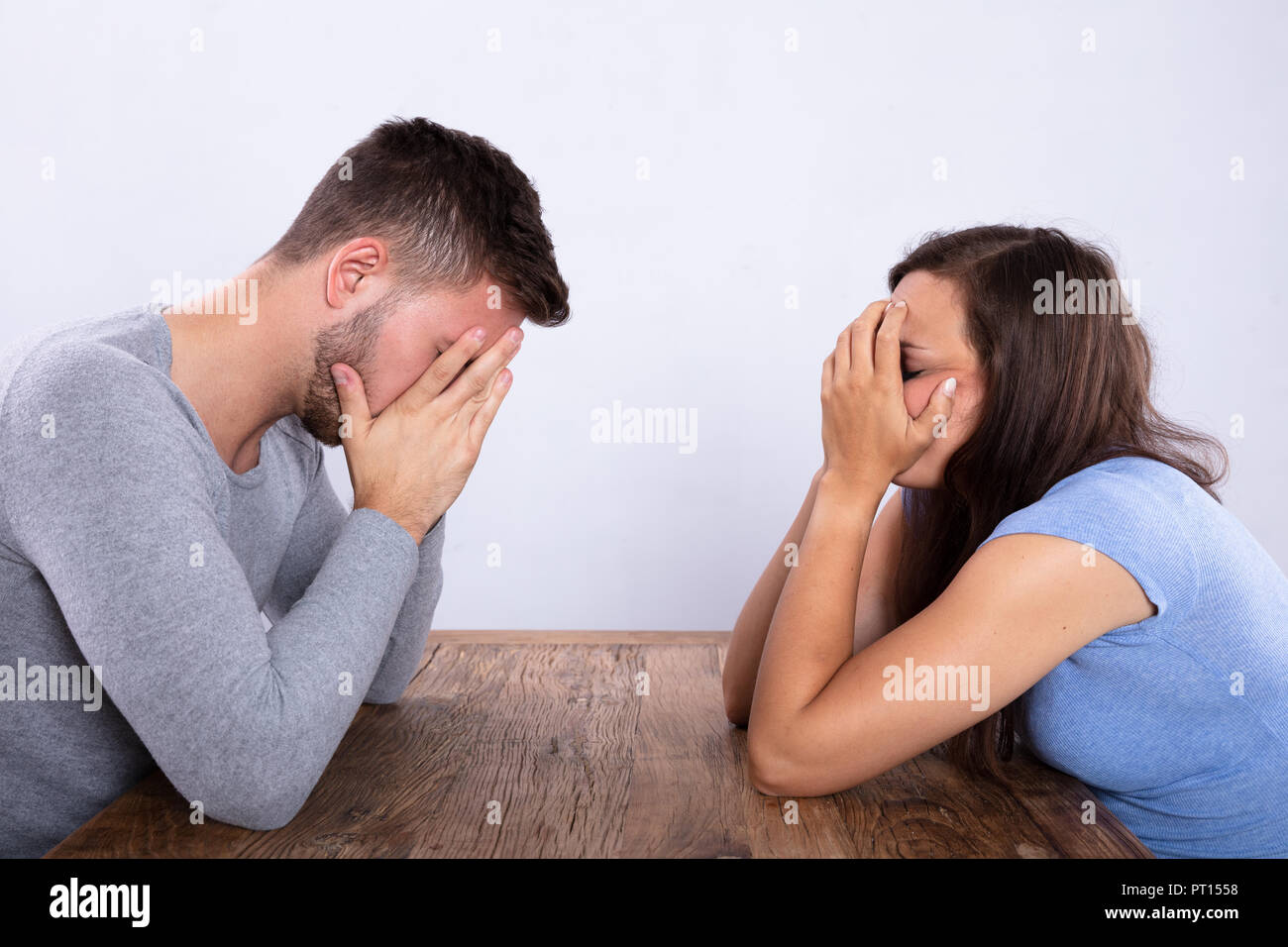 Side View Of A Depressed Young Couple Sitting Opposite Each Other Stock