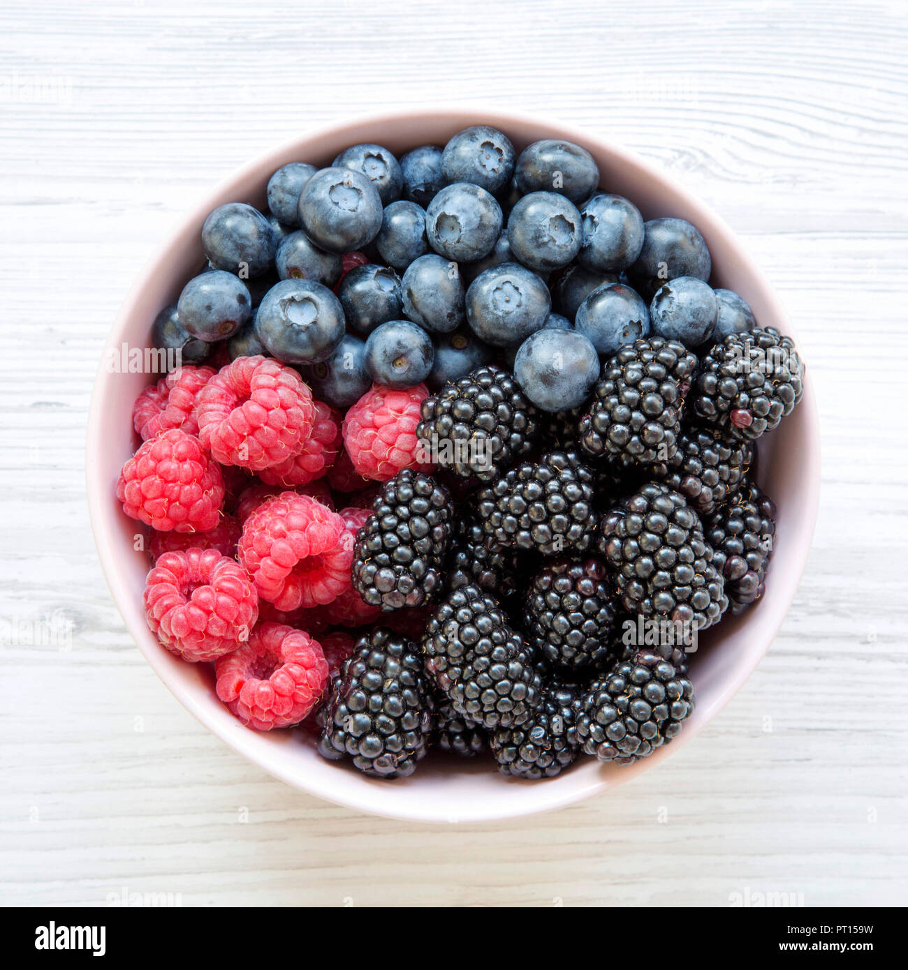 Pink bowl of fresh berries: blackberry, raspberry, blueberry, overhead ...