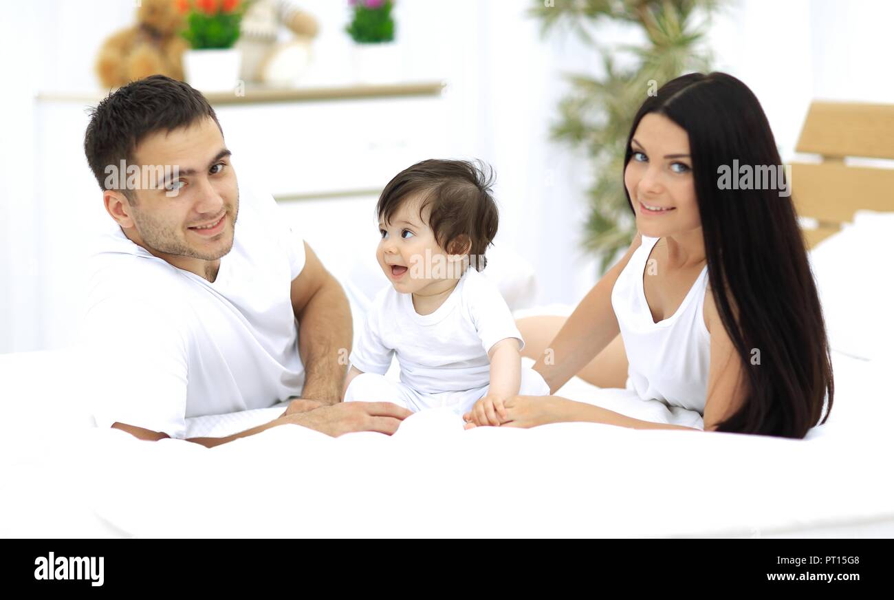 people, family and morning concept - happy child with parents waking up ...