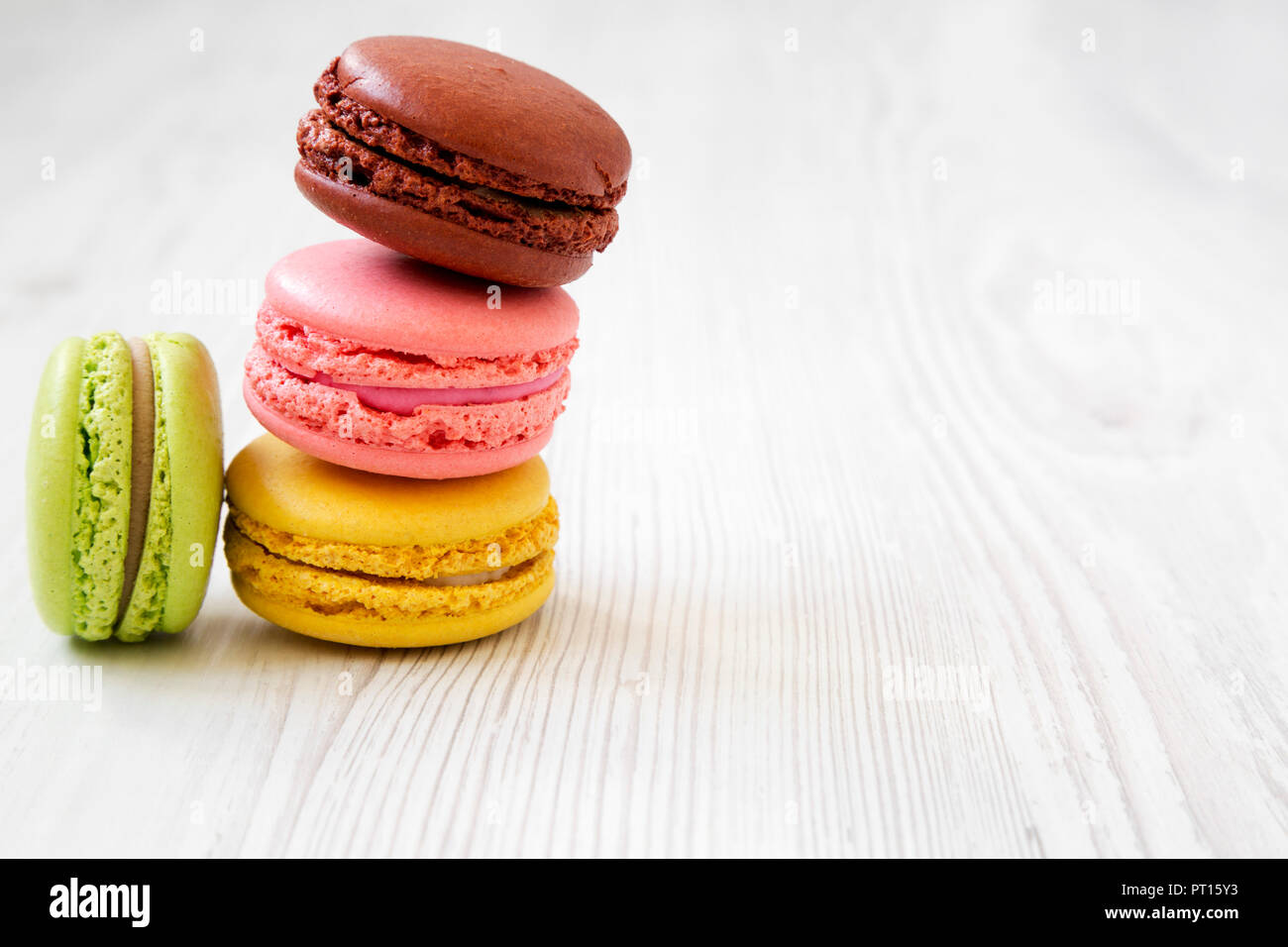 Colorful macarons on a white wooden background, side view. Close-up ...