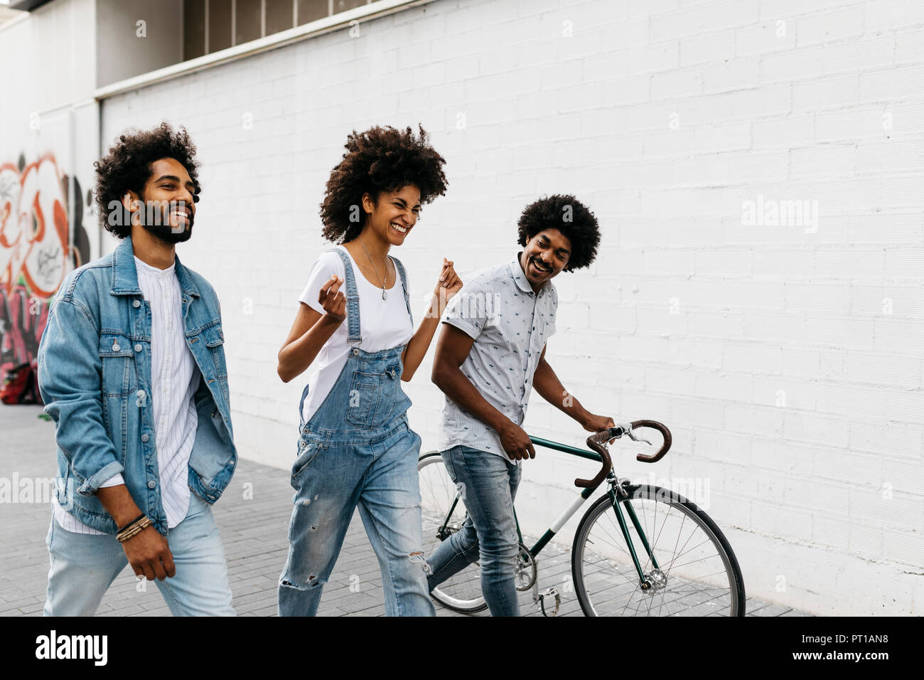 Three friends with racing cycle walking on the street Stock Photo - Alamy
