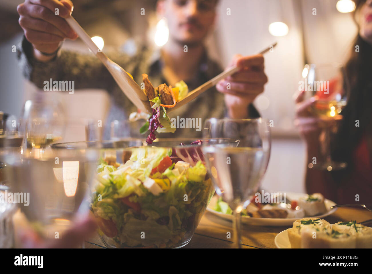Man serving salad at dinner with family and friends Stock Photo - Alamy