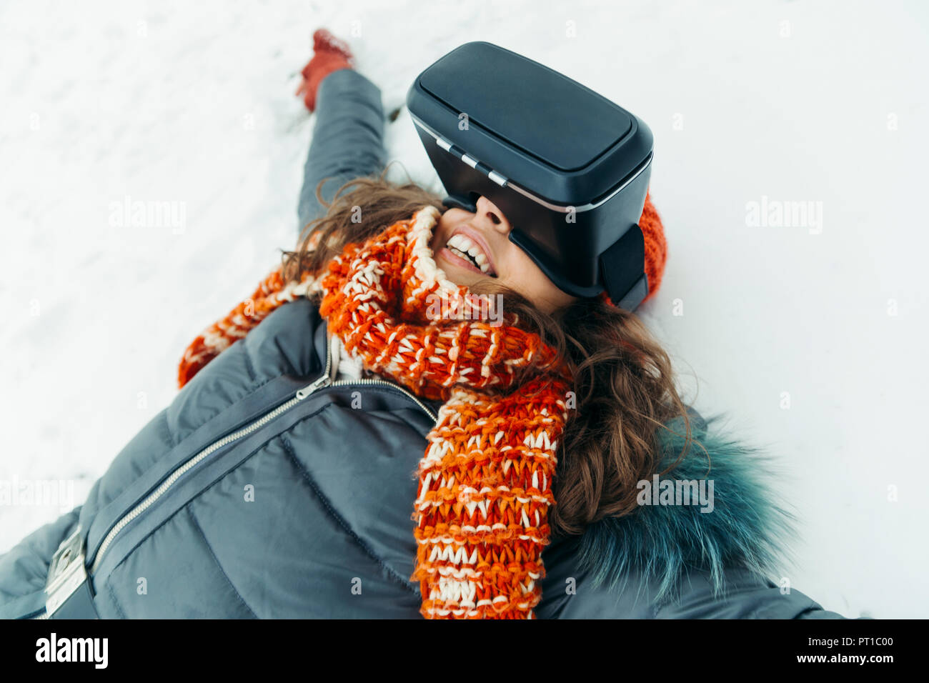 Woman lying in the snow wearing Virtual Reality Glasses Stock Photo - Alamy
