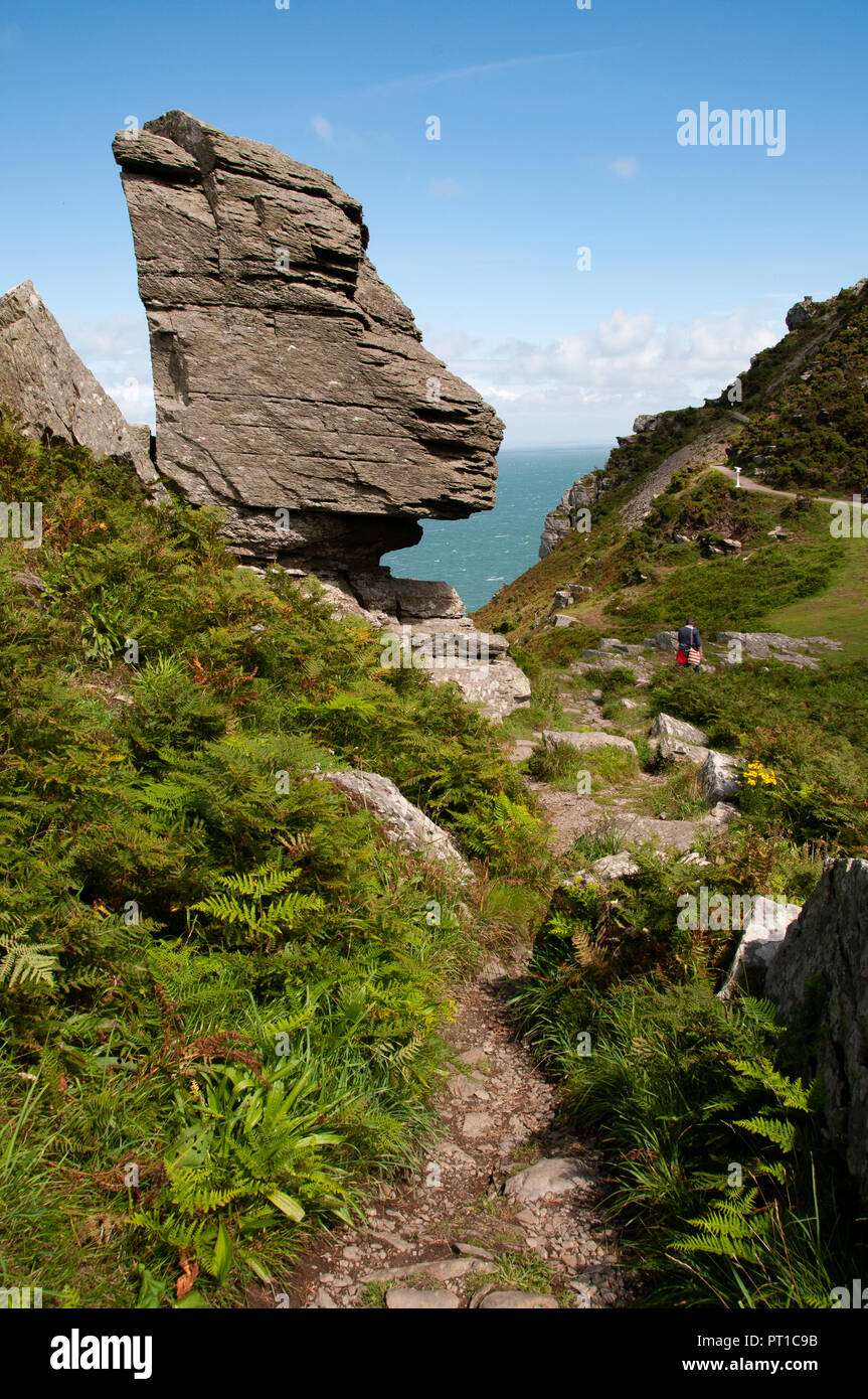 Huge single rock of huge size dwarfing the walkers on the coastal path ...