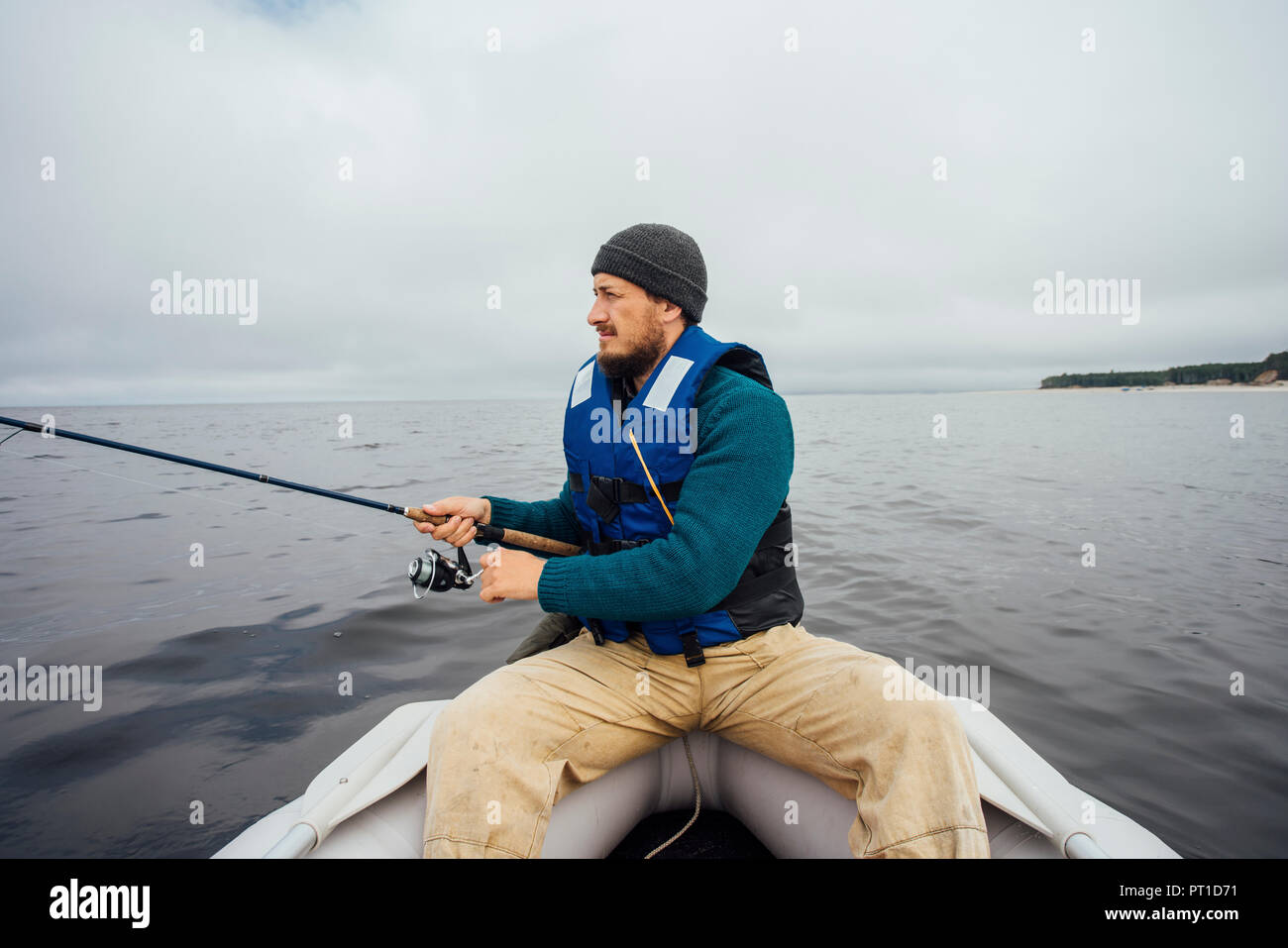 Man sitting on boat fishing with fishing rod Stock Photo - Alamy