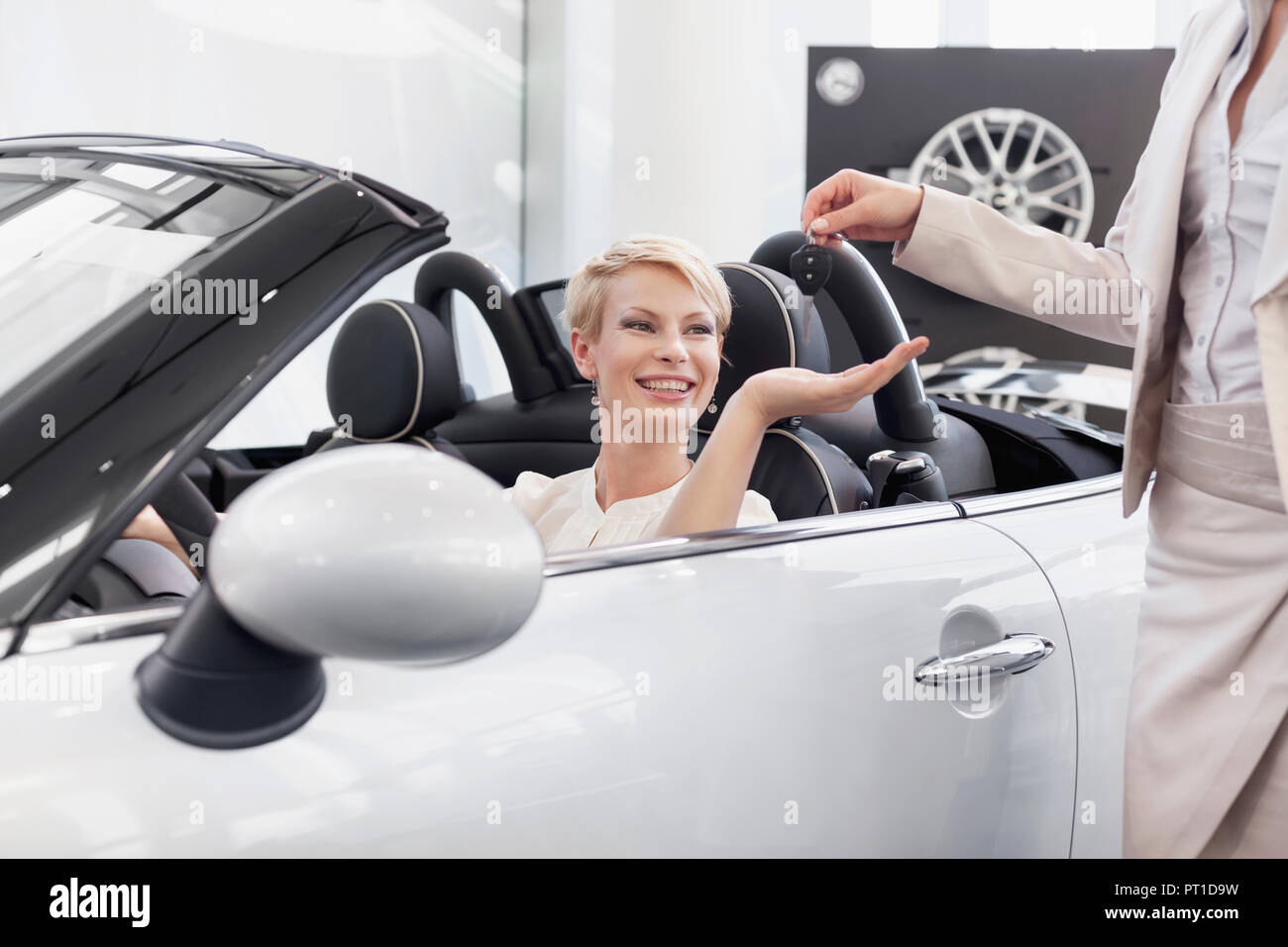 At the car dealer, Woman in convertible receiving car keys Stock Photo ...