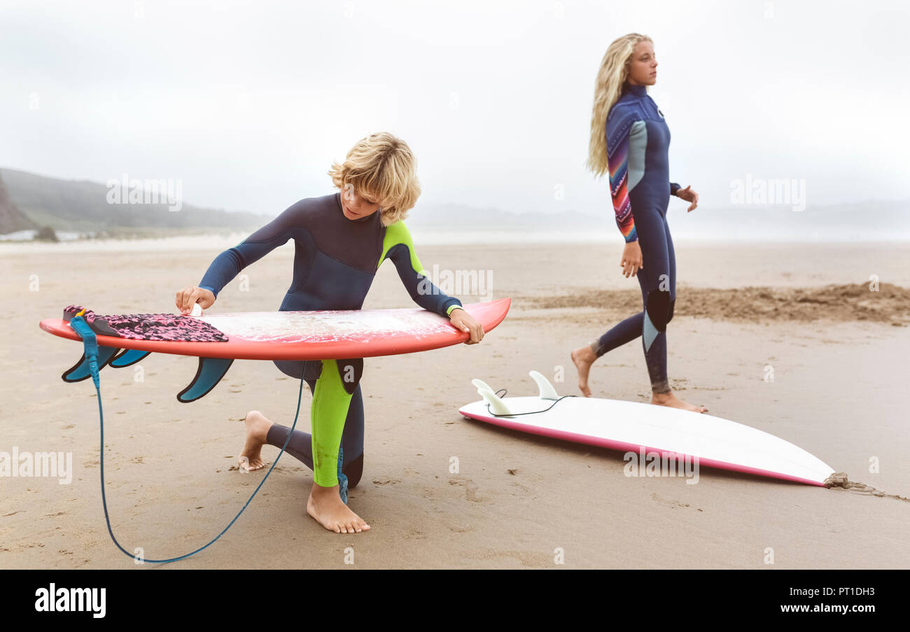 Two young surfers on the beach preparing their surfboards hi-res stock ...