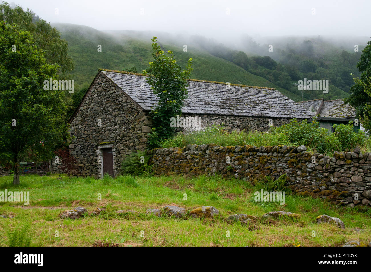 Traditional old slate and stone single storey barn, with drystone walls ...