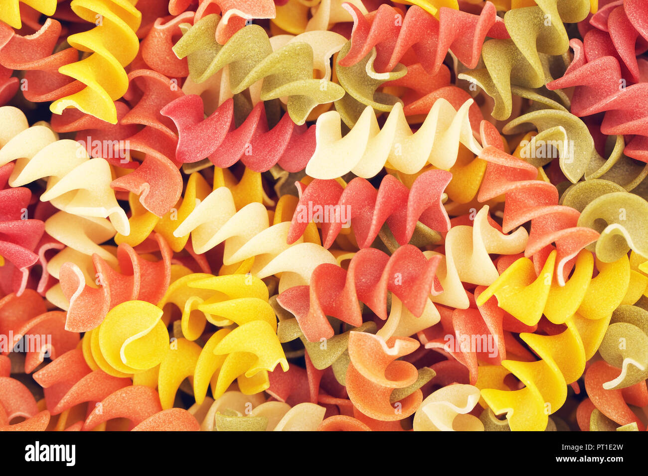 raw spiral pasta of different color, background Stock Photo - Alamy