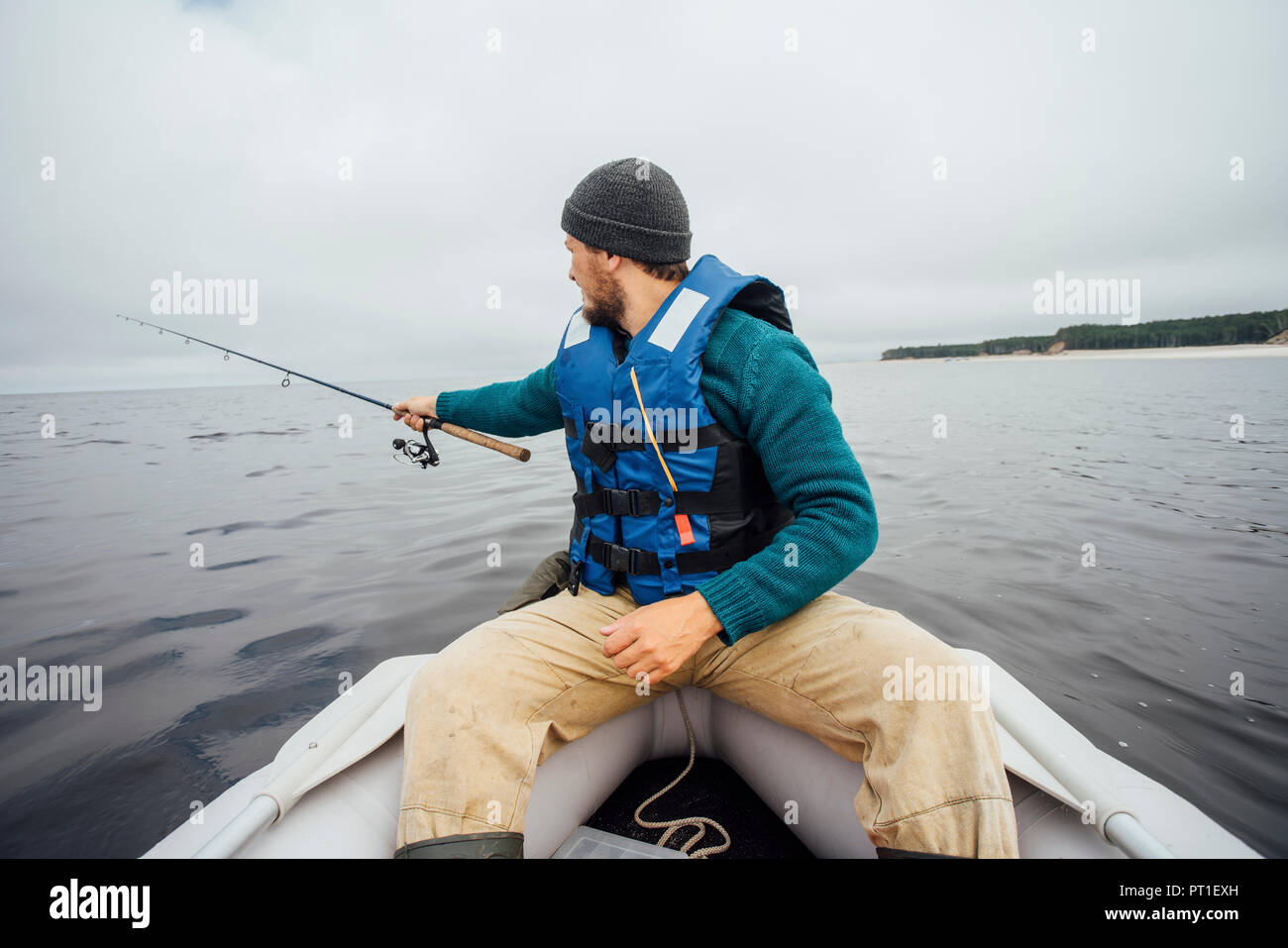 Man sitting on boat fishing with fishing rod Stock Photo - Alamy