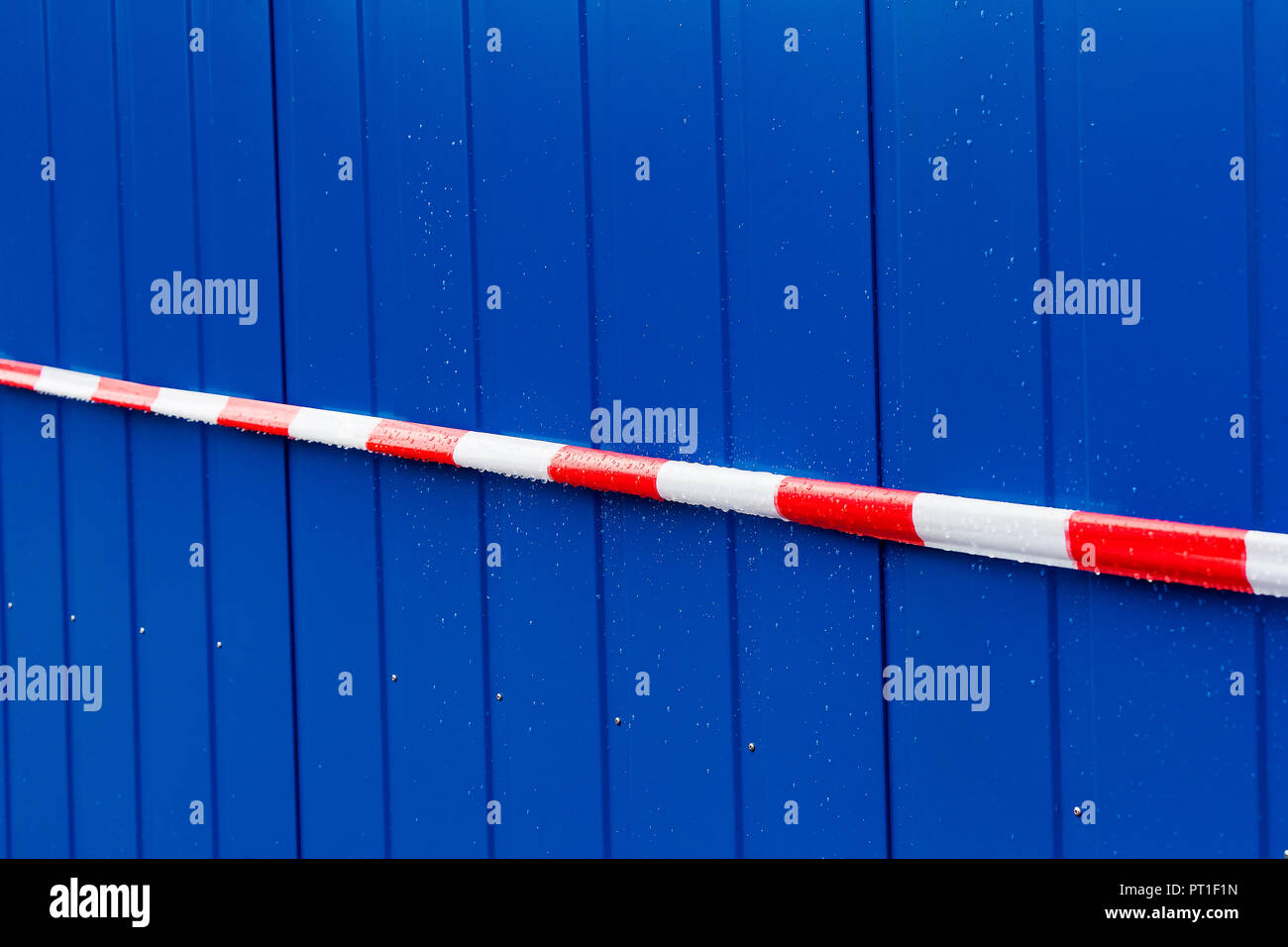 Red and white warning tape on a blue steel background Stock Photo - Alamy
