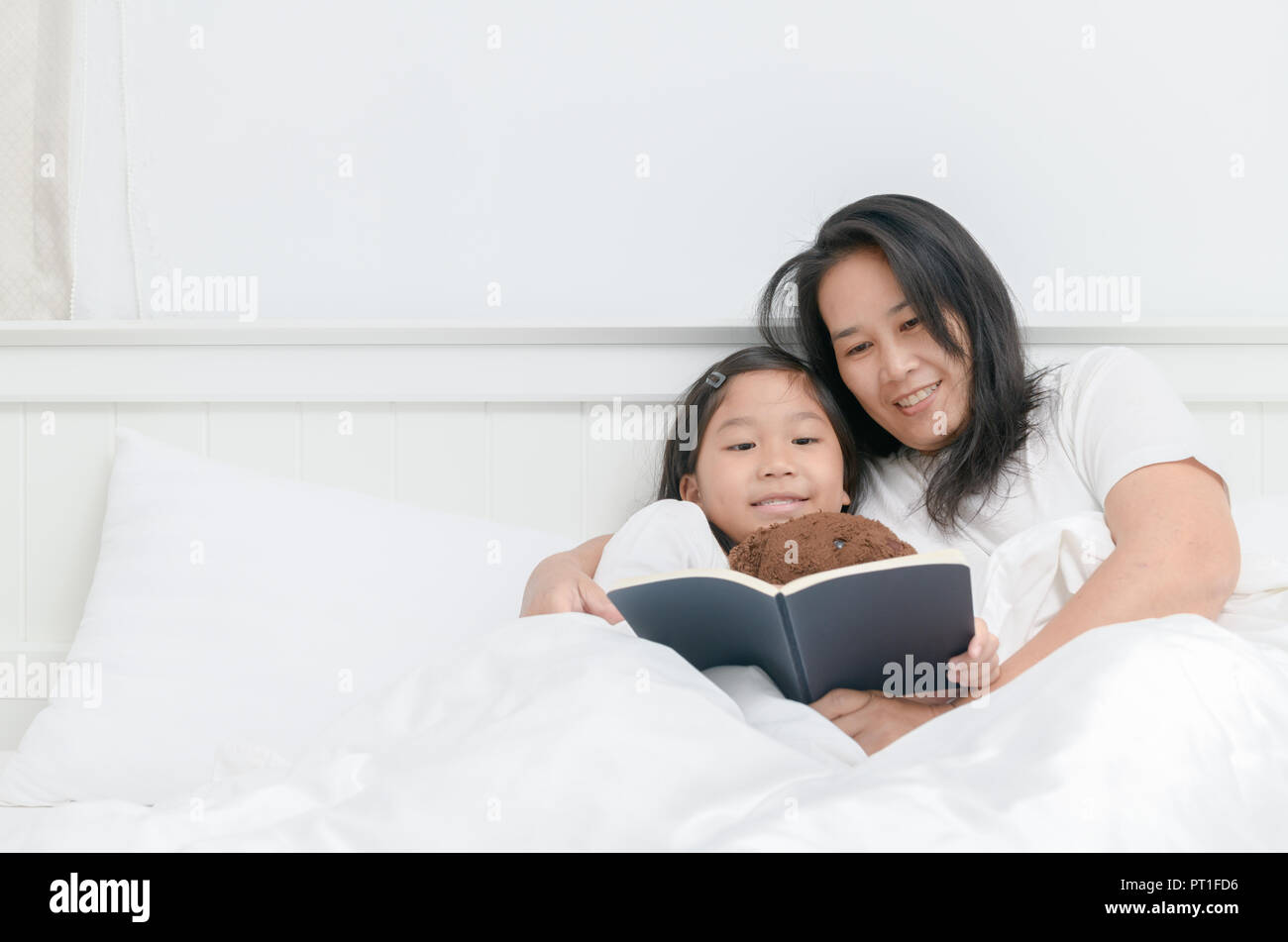 Mother read book with daughter together on bed, education concept Stock ...