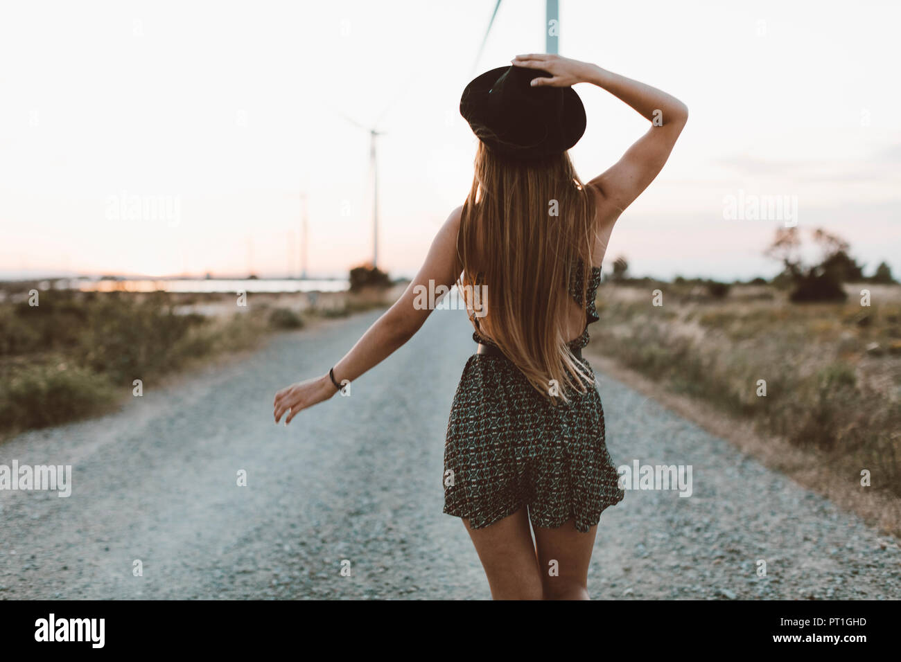 Back view of young woman walking on rural road Stock Photo - Alamy