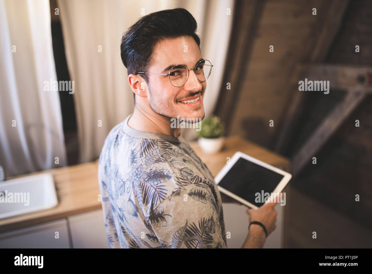 Portrait of smiling young man using tablet at home Stock Photo - Alamy