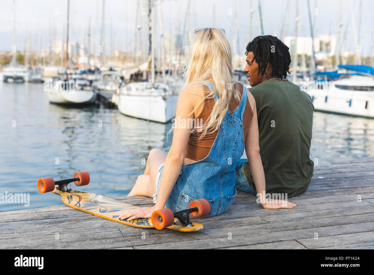 Spain, Barcelona, multicultural young couple with longboard relaxing at ...