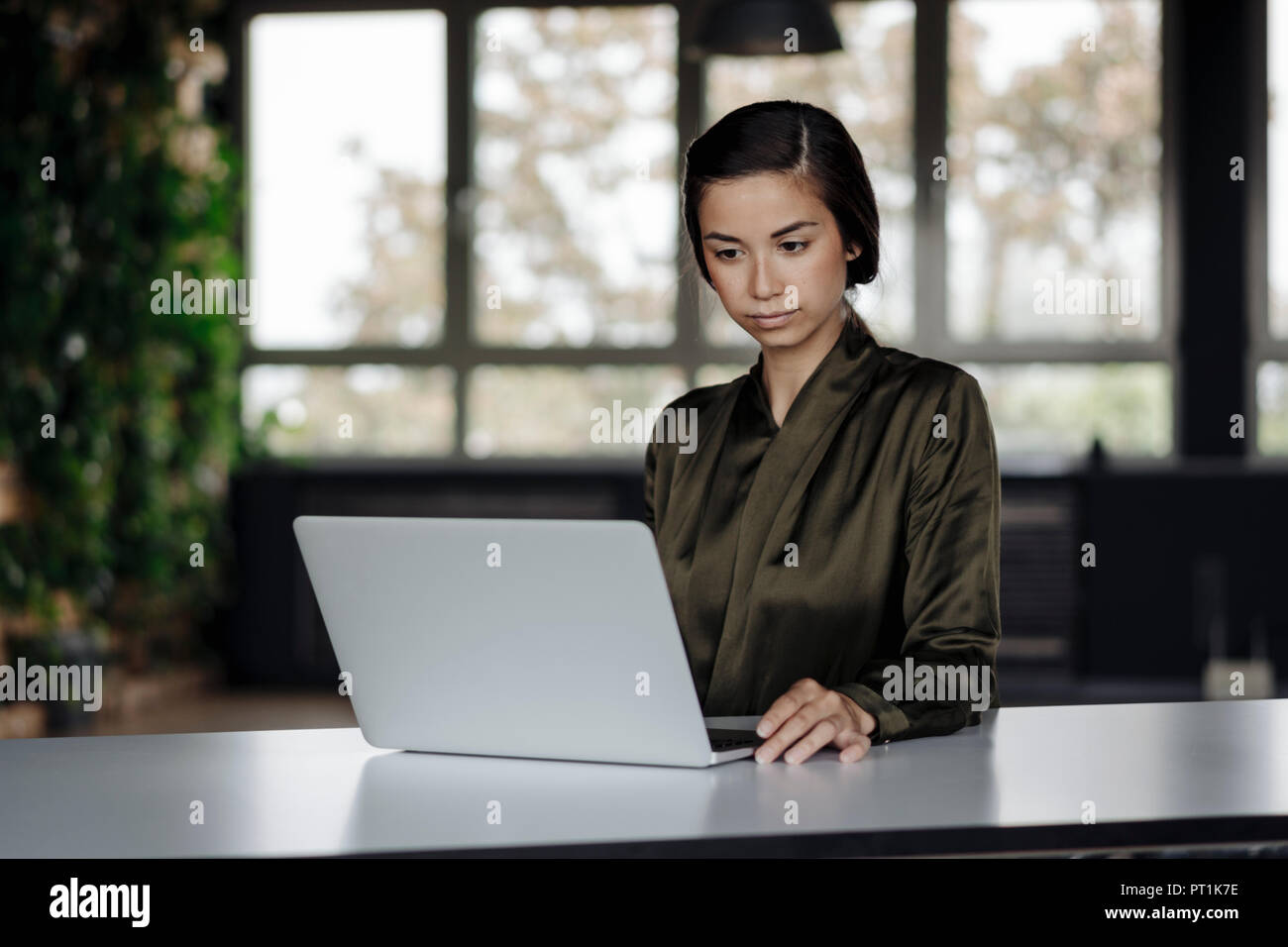 Young woman using laptop in office Stock Photo - Alamy