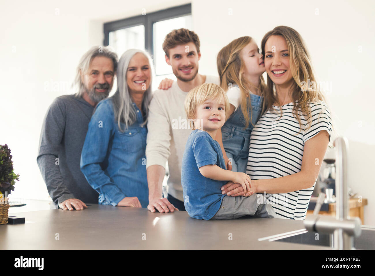 Happy family with grandparents and children standing in the kitchen ...