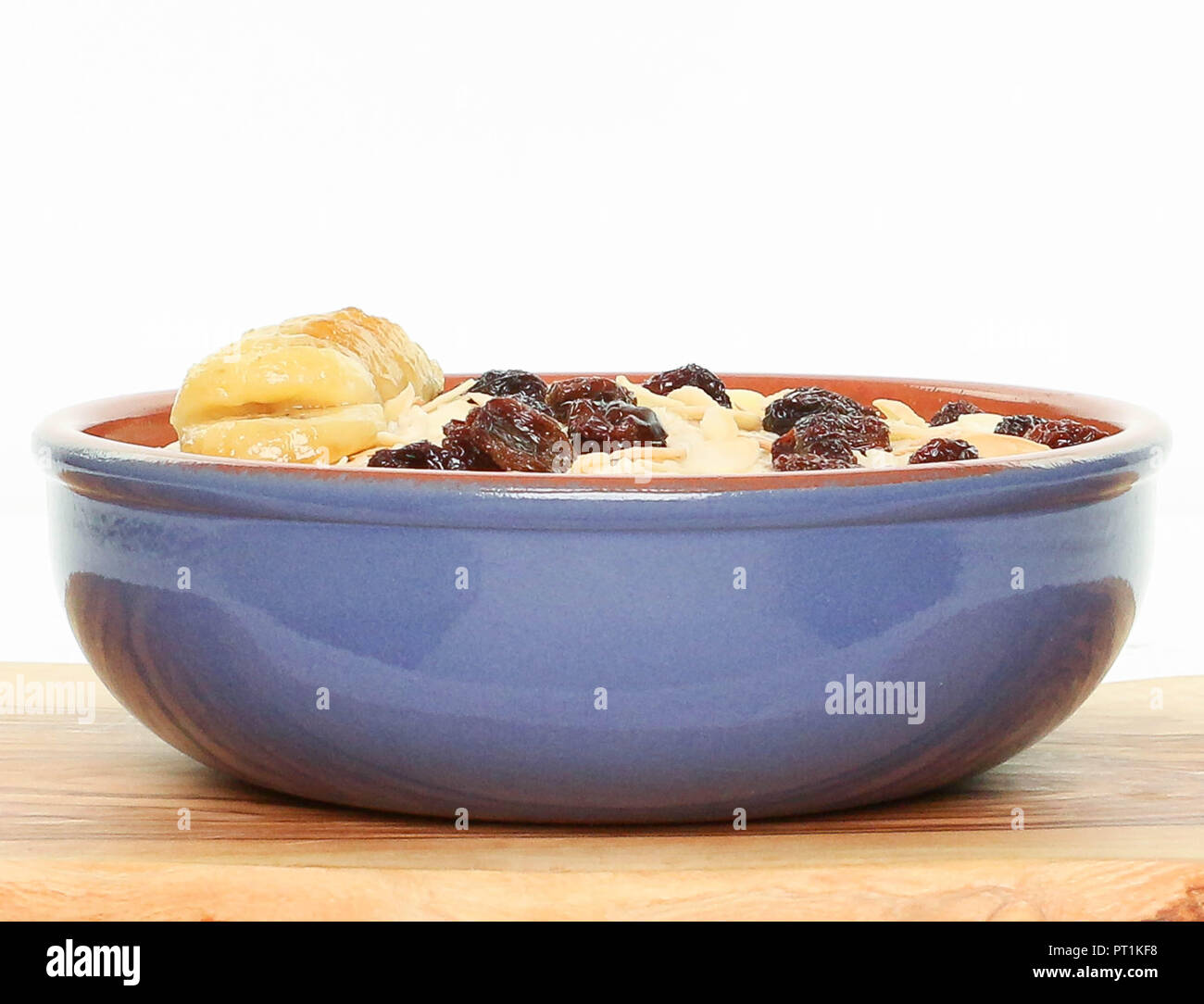 Blue ceramic bowl of porridge with caramelised bananas, raisons and ...